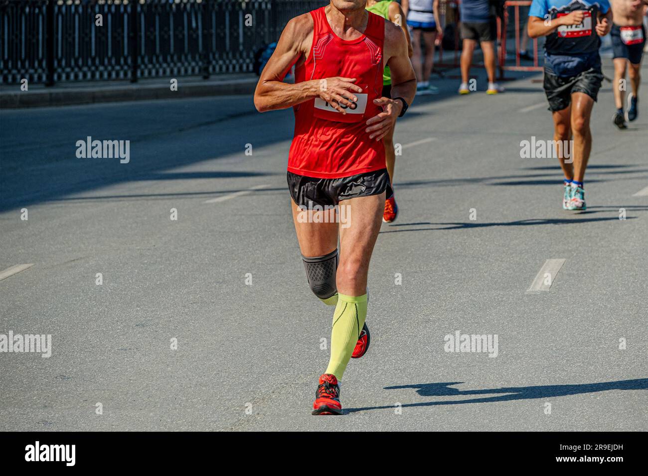 male runner athlete in compression socks and knee pads running marathon ...
