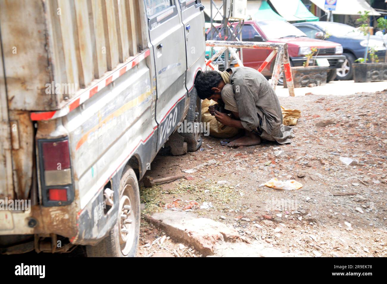A Pakistani drug addict smokes heroin on the side of the road in ...