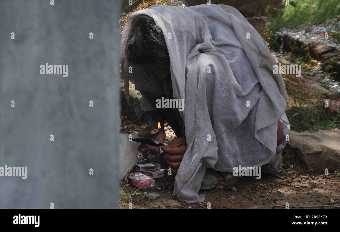 A Pakistani drug addict smokes heroin on the side of the road in ...