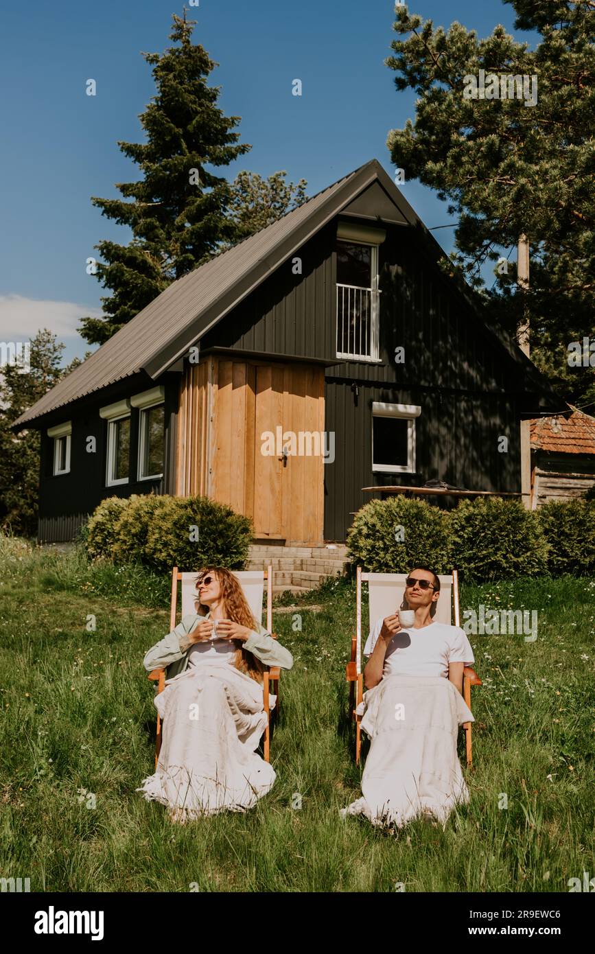 Couple Drinking Coffee and Relaxing outside Cabin Stock Photo - Alamy