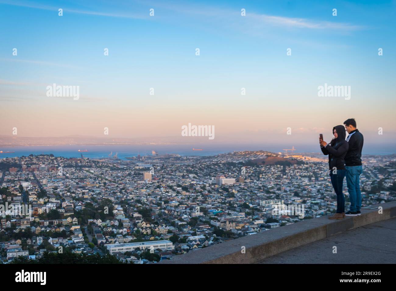A couple standing on top of Twin Peaks Summit in San Francisco taking a ...