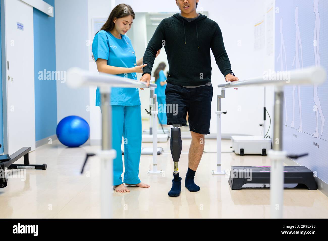 Physiotherapist helping patient with prosthetic leg at parallel bars ...