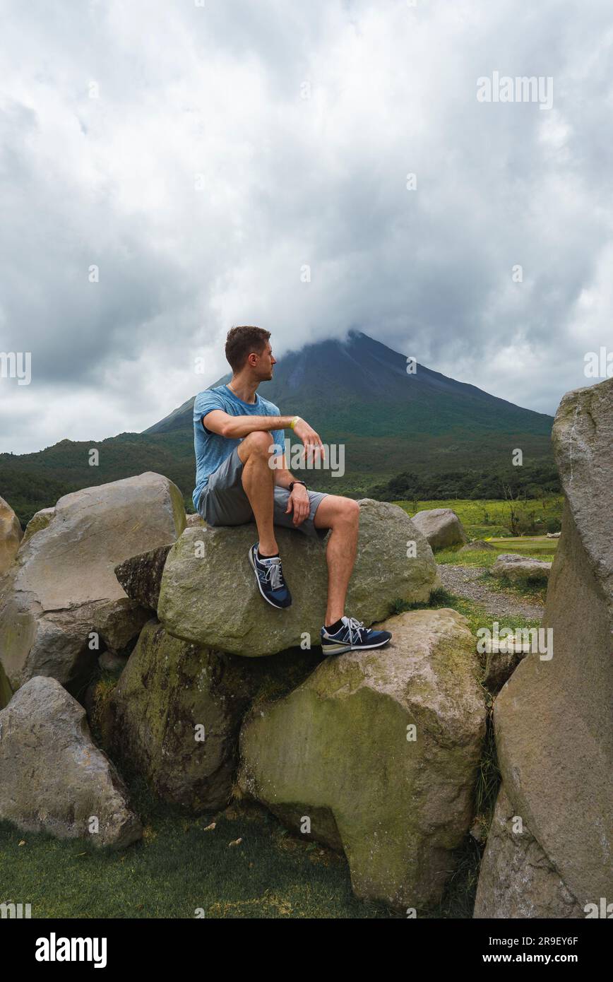 Male hiker looking out at the Arenal volcano in Costa Rica Stock Photo ...