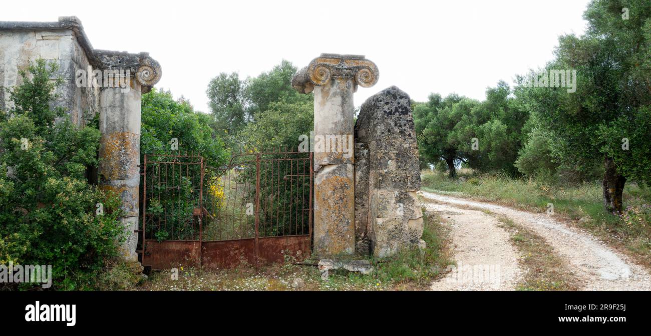 A ruined stone gateway with iron gates on ionic columns in the ...
