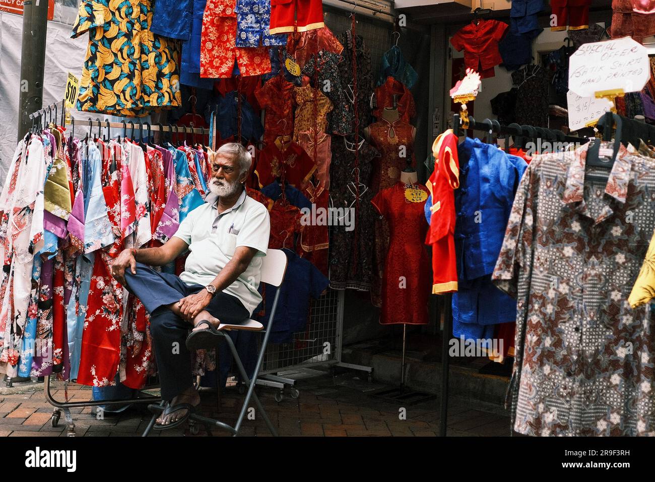 An adult male seated in an outdoor chair in front of an apparel store ...