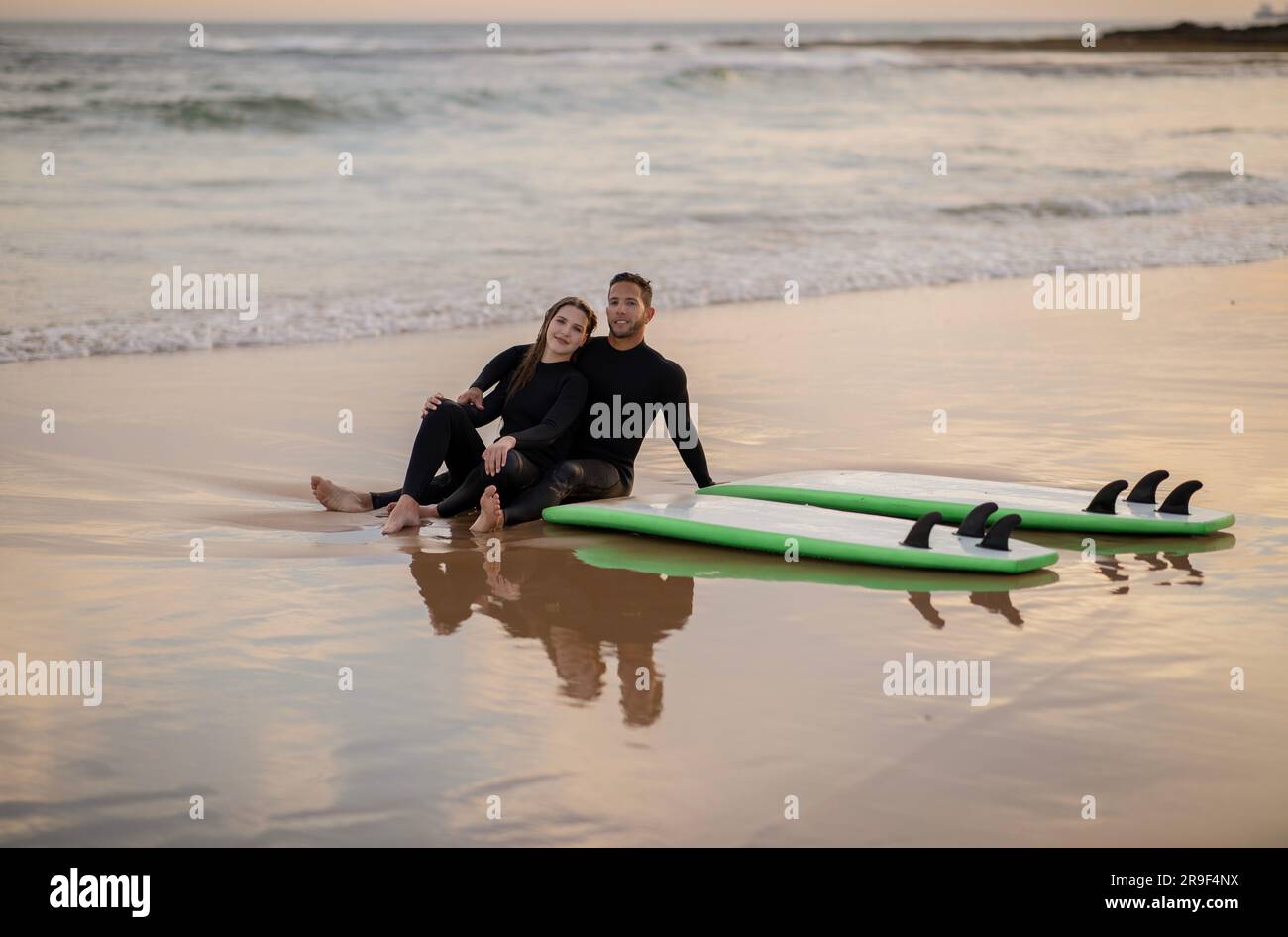 Surf Date. Young Beautiful Couple Relaxing On The Beach After Surfing ...
