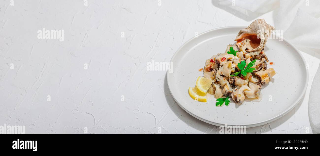 Rapana clam meat with oil, spices and greens. Healthy seafood is rich ...