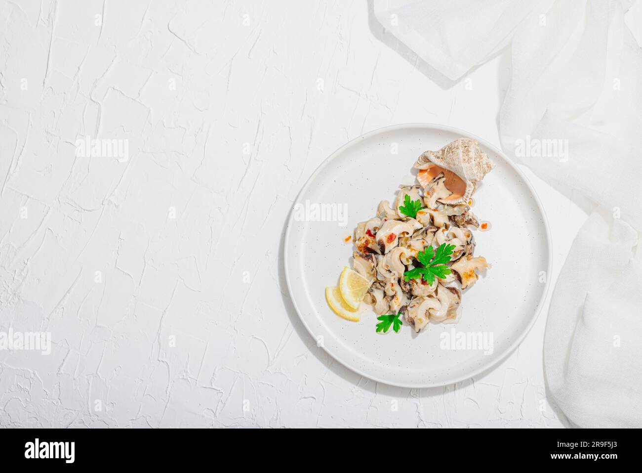 Rapana clam meat with oil, spices and greens. Healthy seafood is rich ...