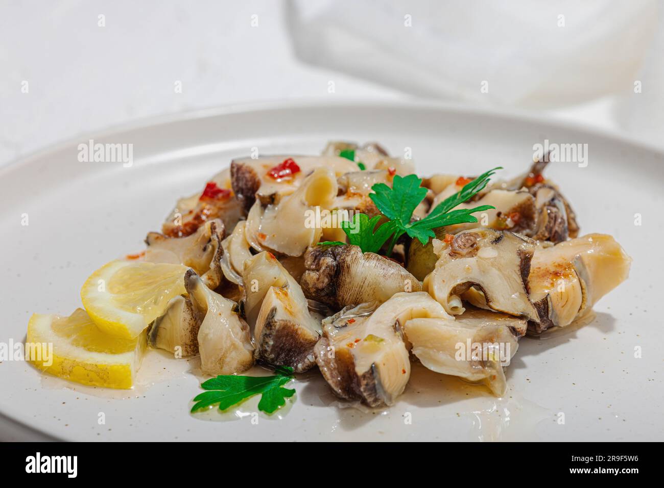Rapana clam meat with oil, spices and greens. Healthy seafood is rich ...