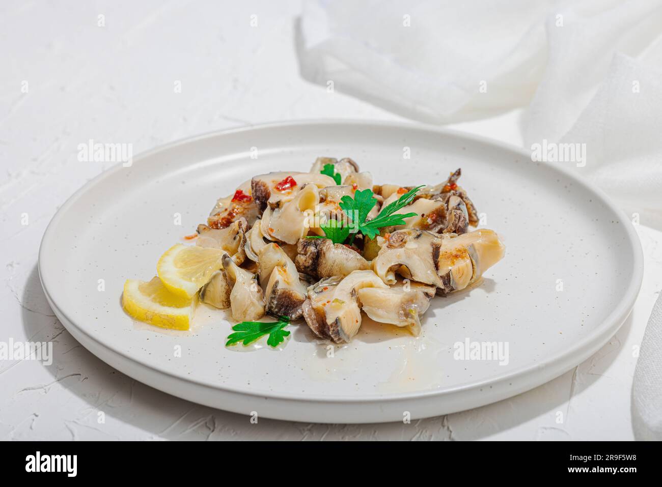 Rapana clam meat with oil, spices and greens. Healthy seafood is rich ...