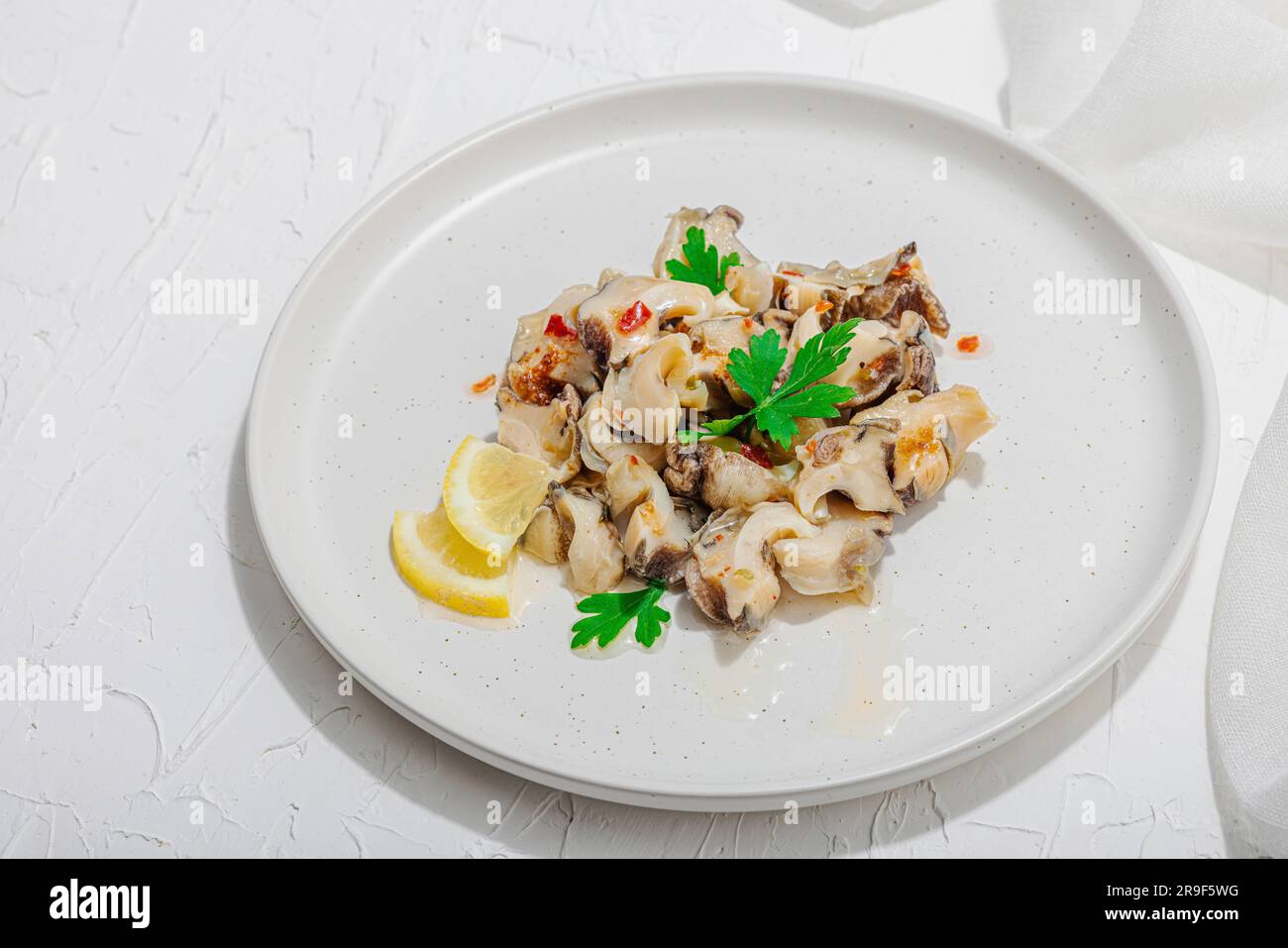 Rapana clam meat with oil, spices and greens. Healthy seafood is rich ...