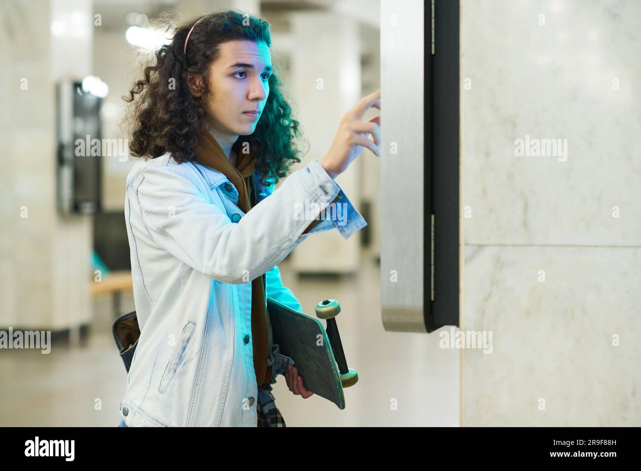 Serious teenage guy scrolling through timetable of subway trains while ...