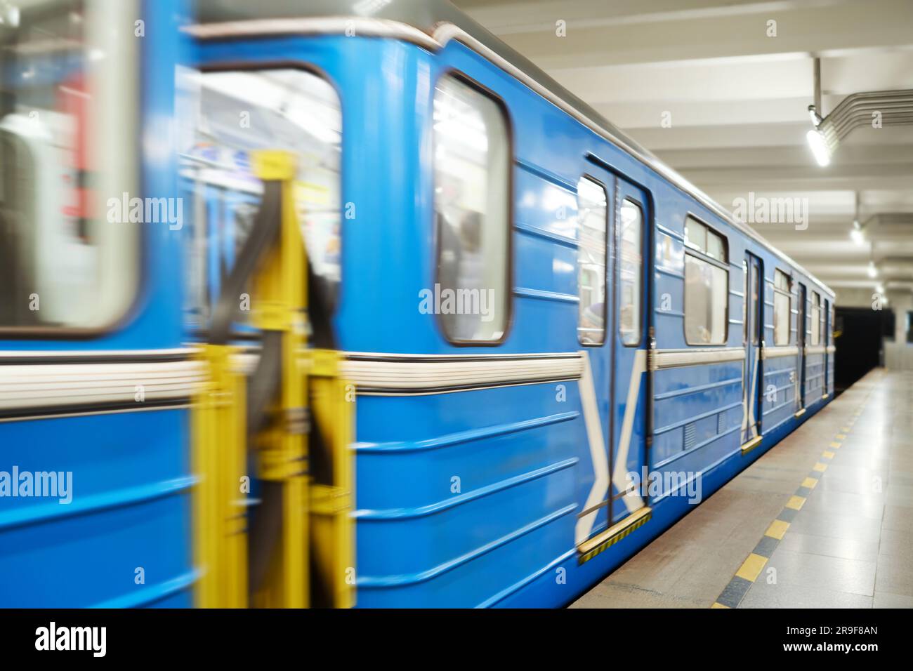 Perspective view of long blue subway train with people inside moving ...