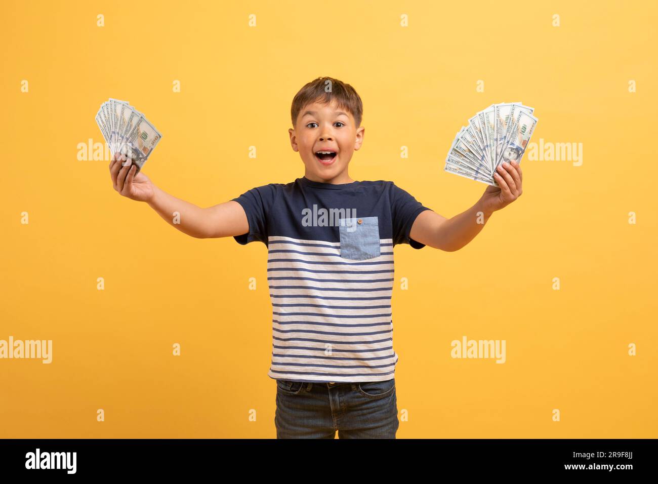 Thrilled kid cute boy holding money cash in both hands Stock Photo - Alamy
