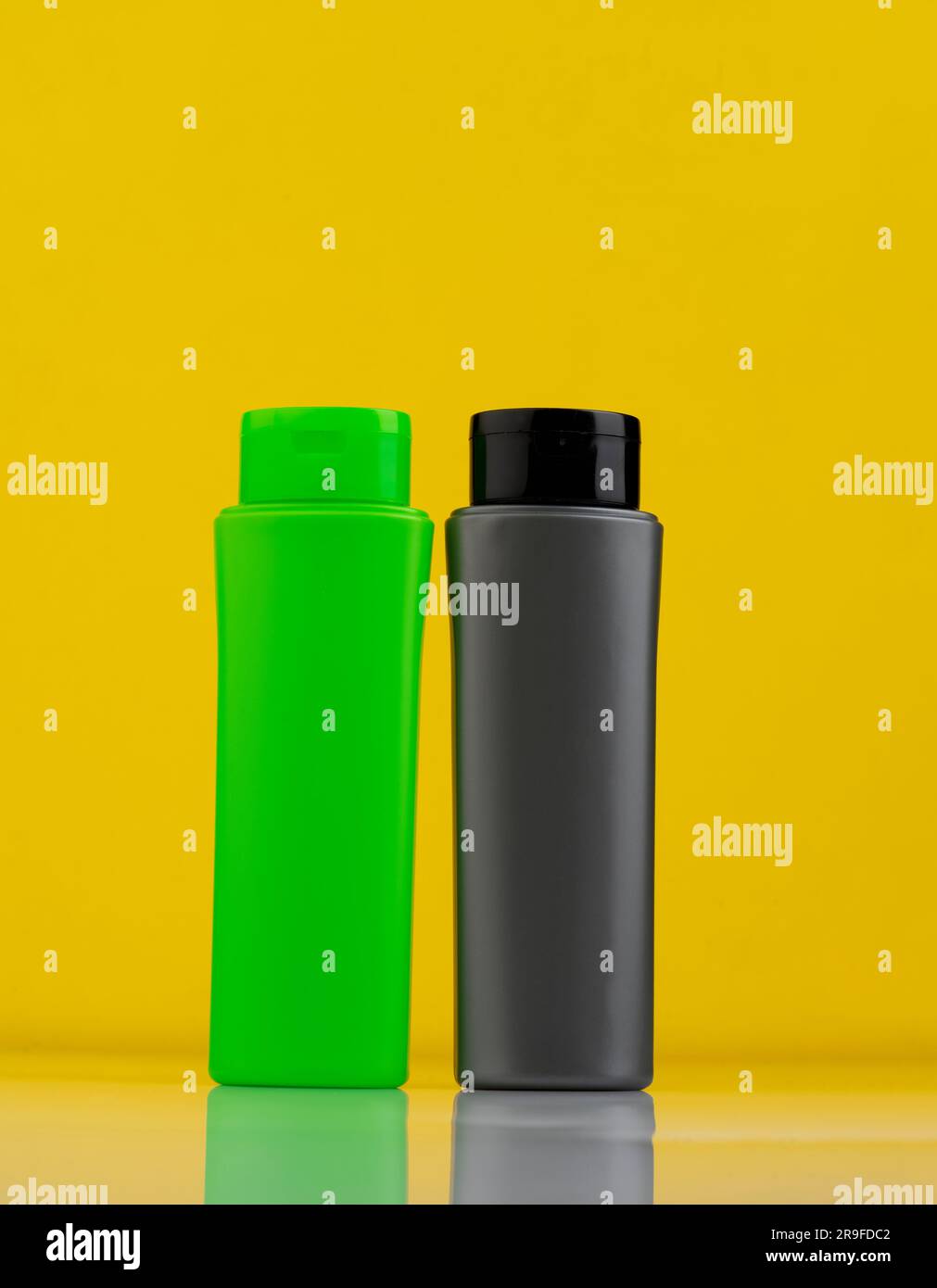 Two clear plastic bottles, one green and one black, set against a ...