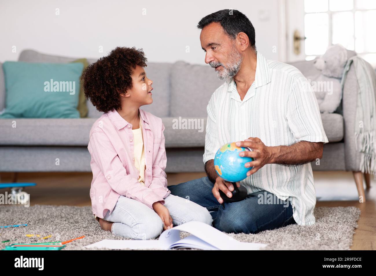 Latin Grandpa Talking To Grandson Holding World Globe At Home Stock ...