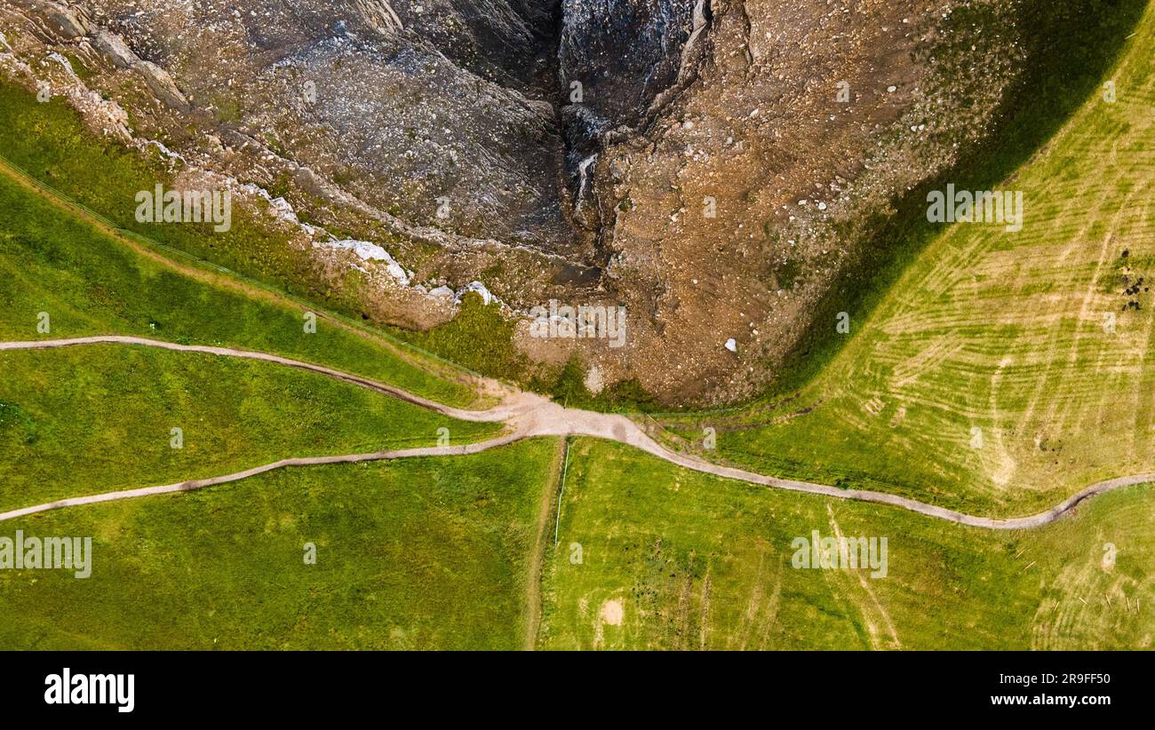 Top down aerial of a mountain ridge in the dolemites with a green side ...