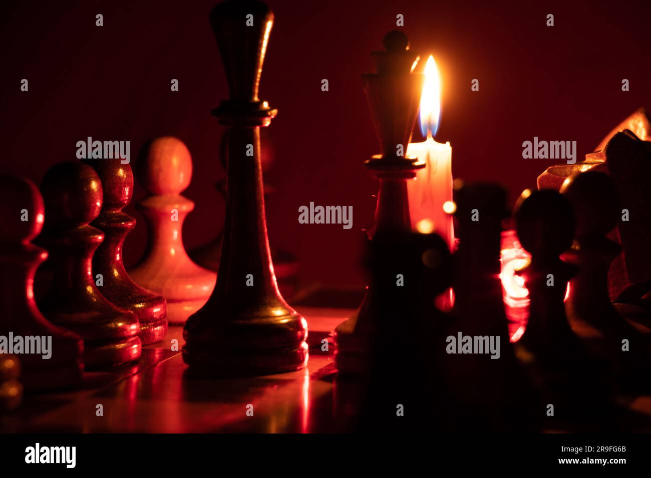 chess pieces stand on a chessboard and next to a burning candle in the ...