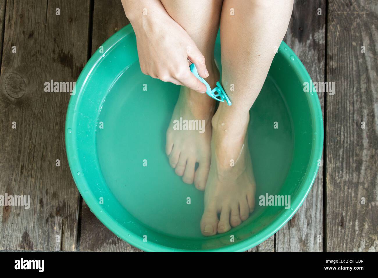 The Girl Washes Her Legs And Shaves Them With A Tanok In A Green Bowl