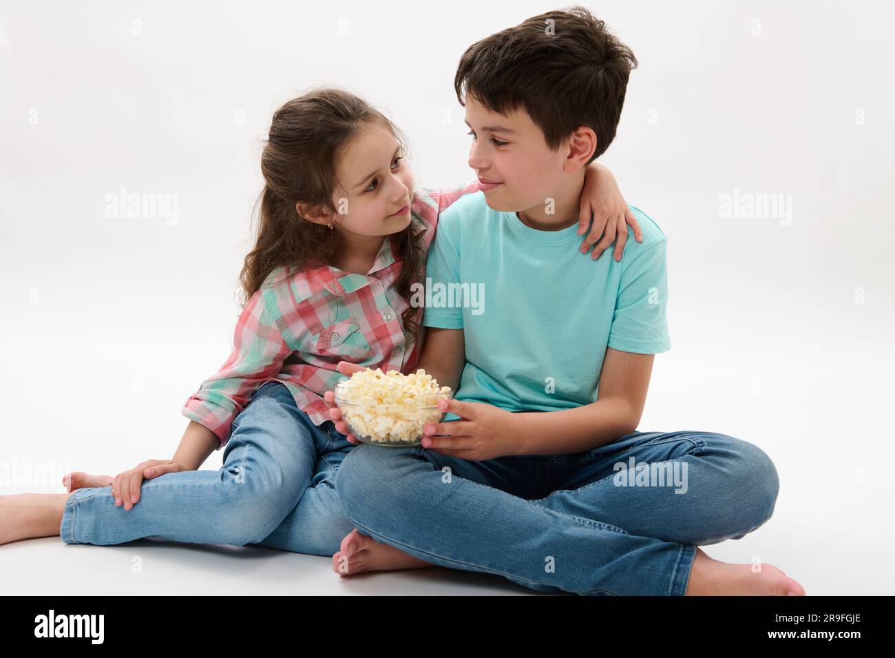 Adorable nice kid girl gently hugs her brother serving her a bowl of ...