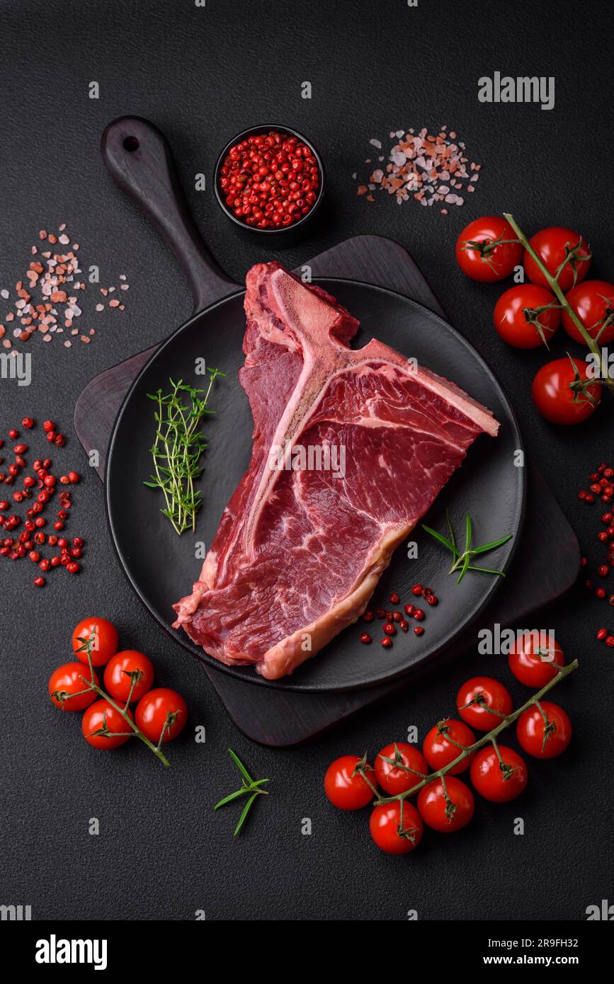 Raw juicy beef t-bone steak with salt, spices and herbs on a textured ...