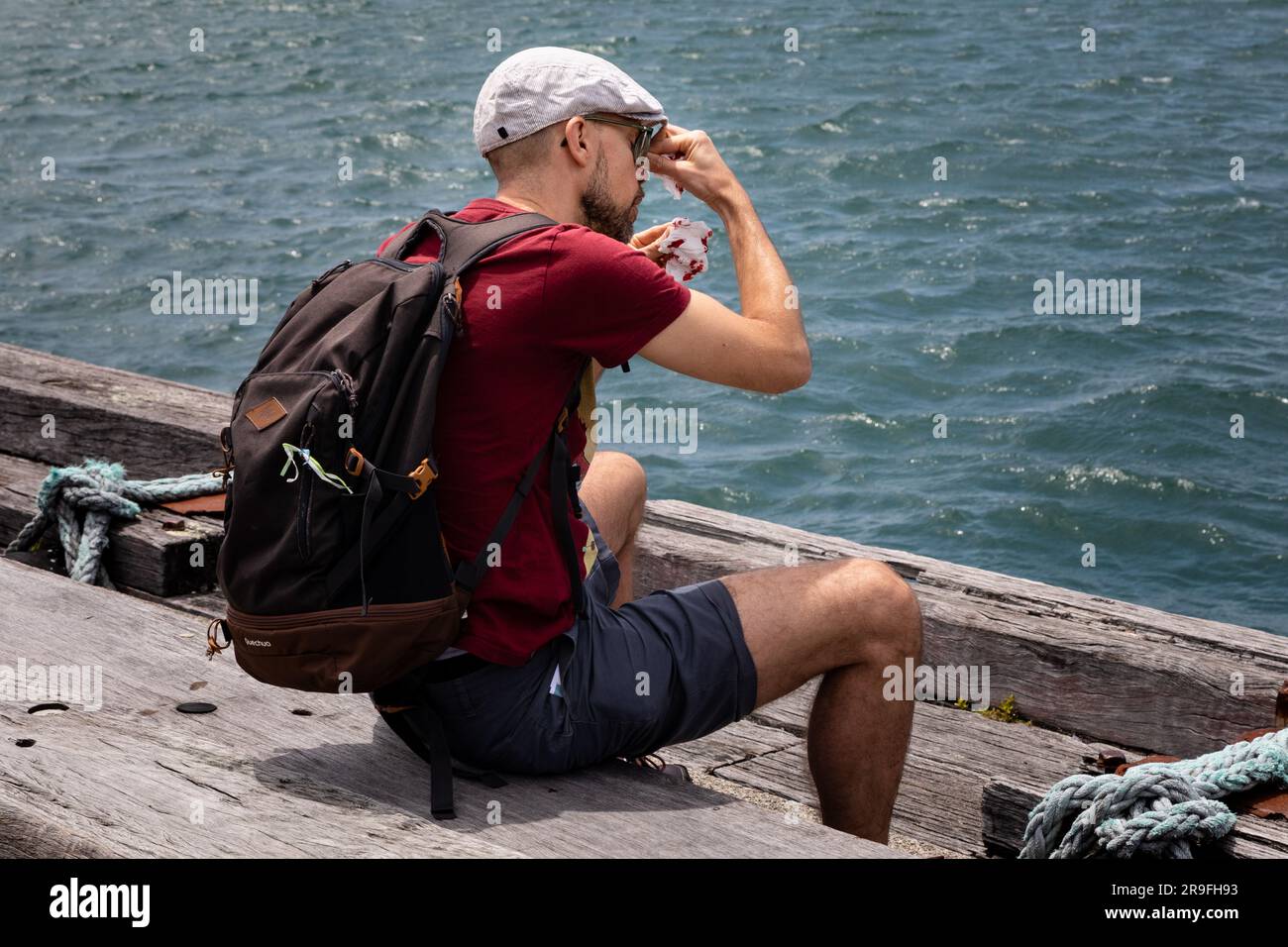 A man tourist with a bleeding nose nosebleed on the sea wall in the ...