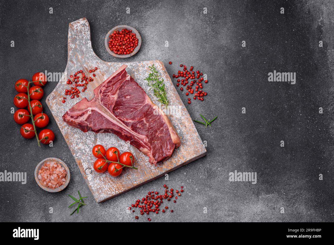 Raw juicy beef t-bone steak with salt, spices and herbs on a textured ...