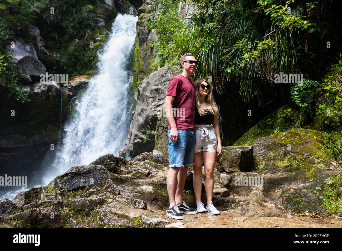 A couple pose at Wainui Falls Waterfalls Wainui Bay, Tasman Region, New Zealand, South Island ...