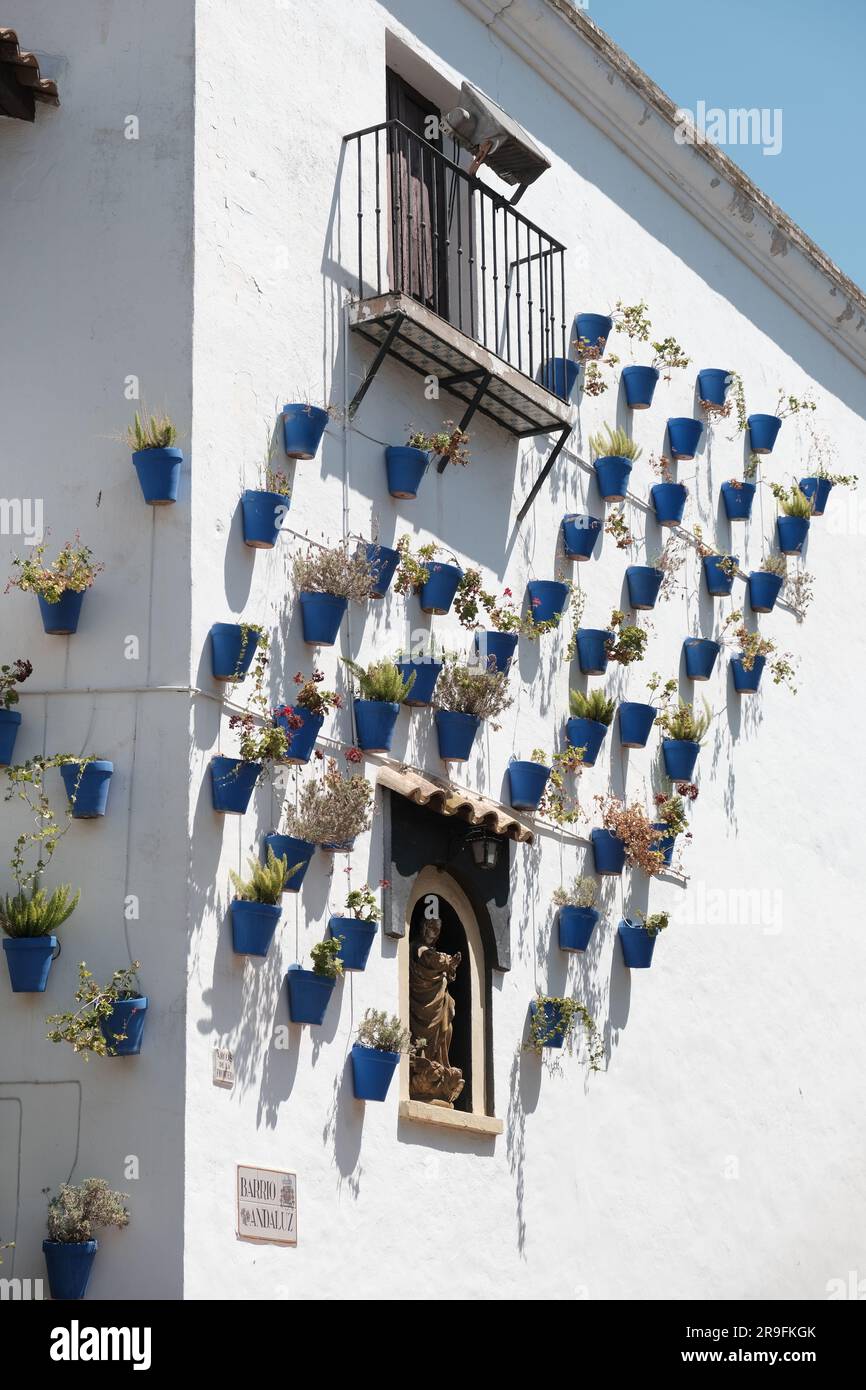 A white brick wall with two blue flower pots attached to it by metal ...