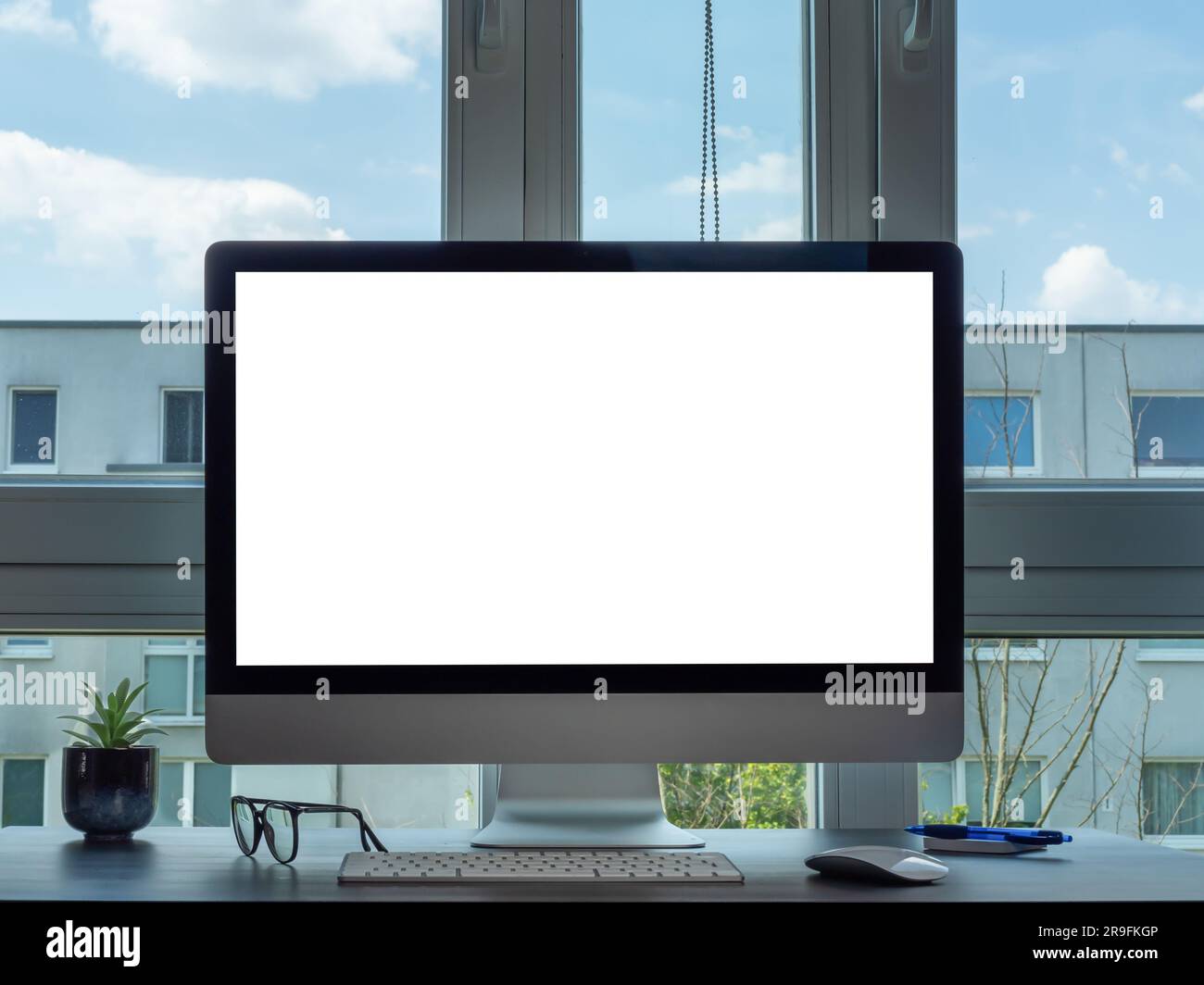 The computer is on the desk by the window. The computer has a white ...