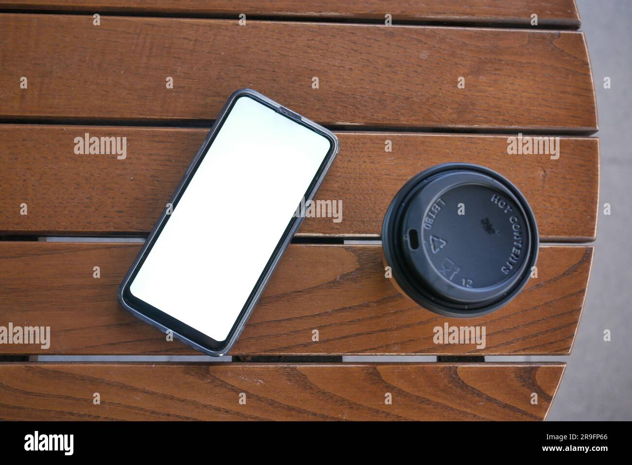 Blank take away kraft coffee cup and smart phone with white screen on ...
