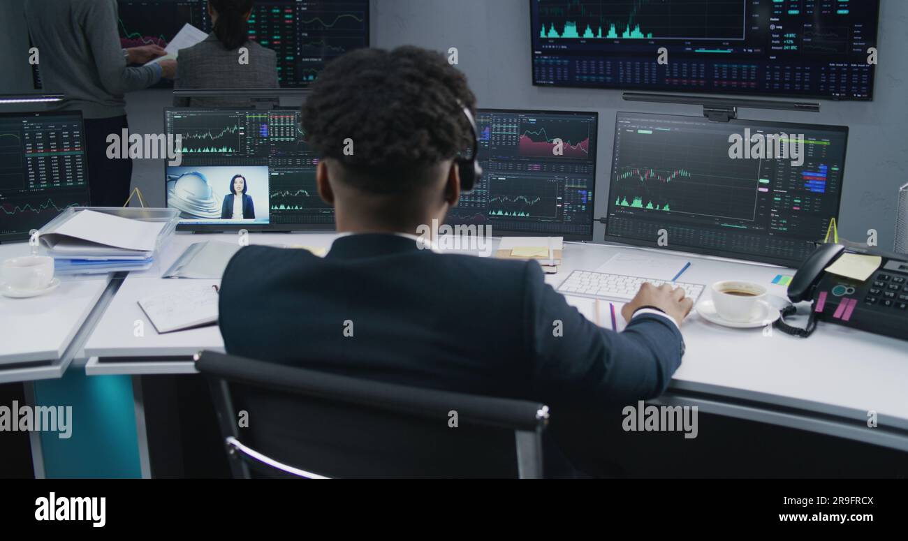 African American trader works at computer with displayed real-time ...