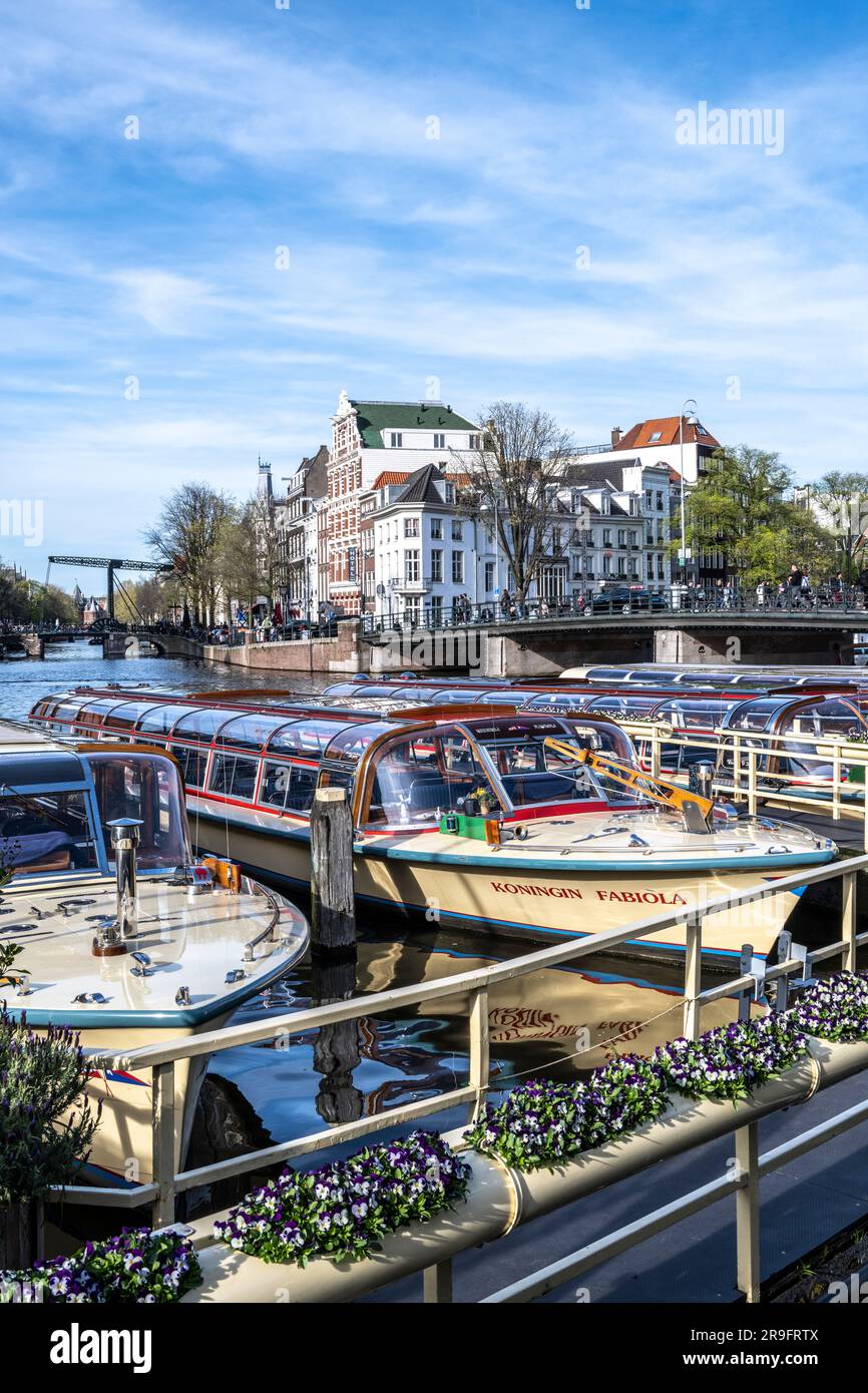 tour boats docked on the Amstel River in Rembrandt Plein in Amsterdam ...