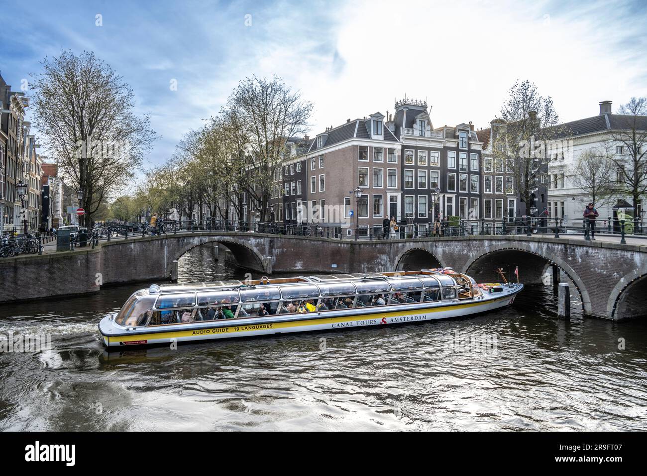 canal tour boat going under a bridge in Amsterdam Stock Photo - Alamy
