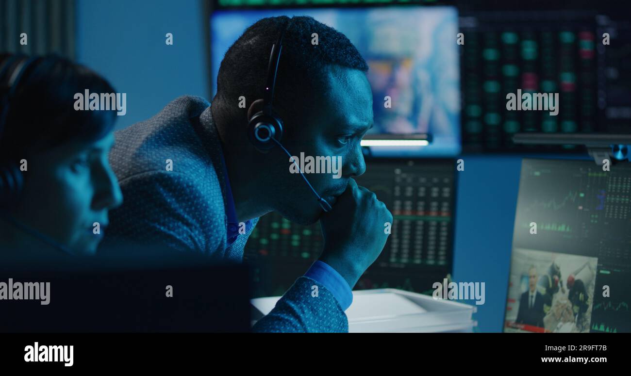 Multracial financial analysts, businesspeople monitor real-time stocks ...