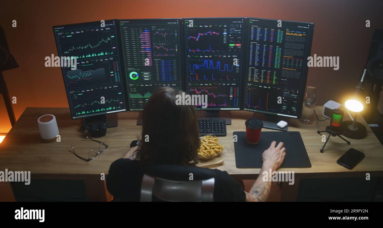Back view of male stock trader watching real-time stocks, exchange market charts on multi ...