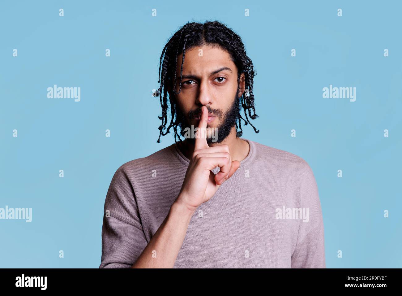 Arab man making quiet gesture and holding forefinger on lips portrait ...