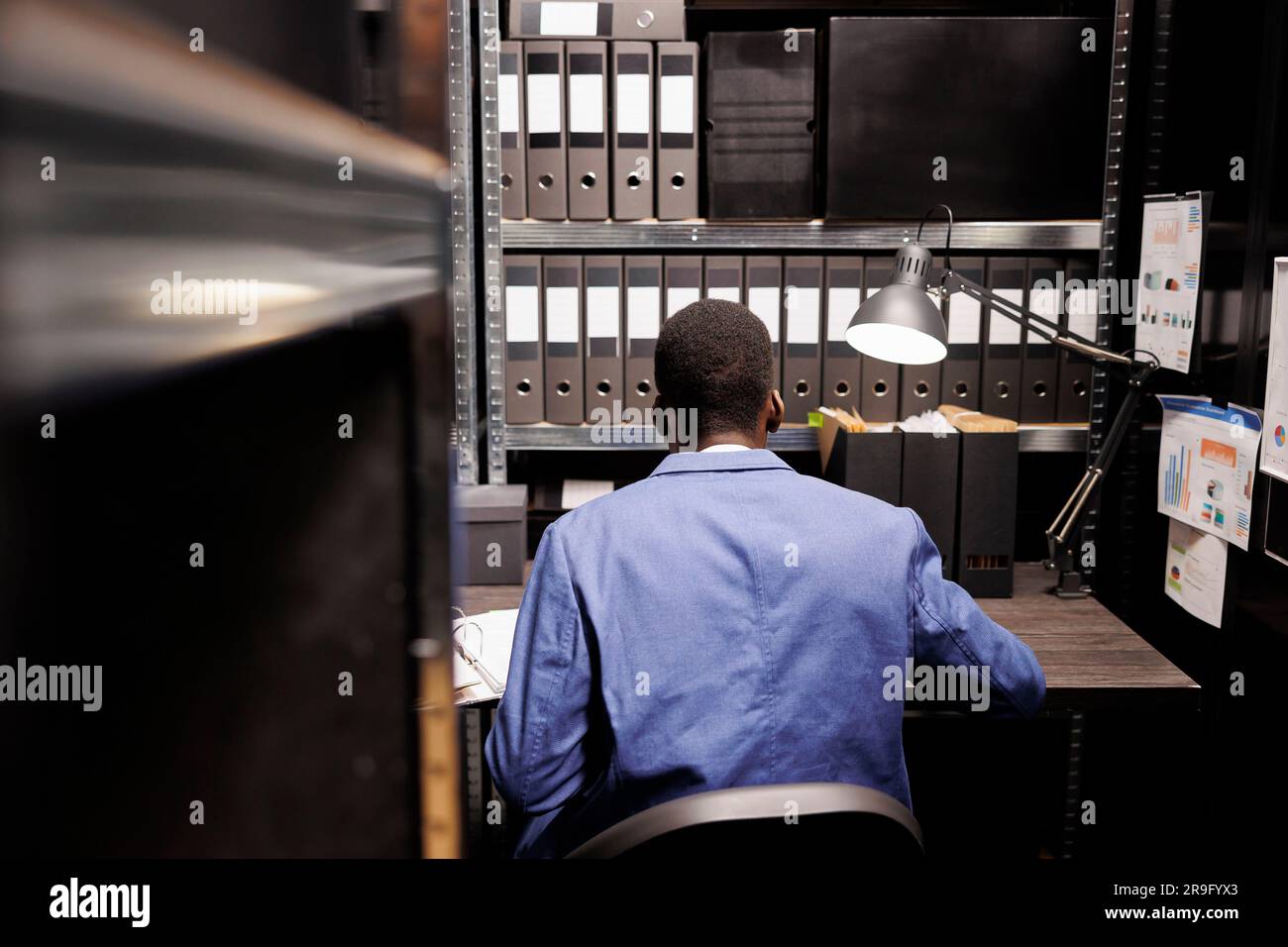 Bookkeeper sitting at desk in storage room, working at bureaucracy ...