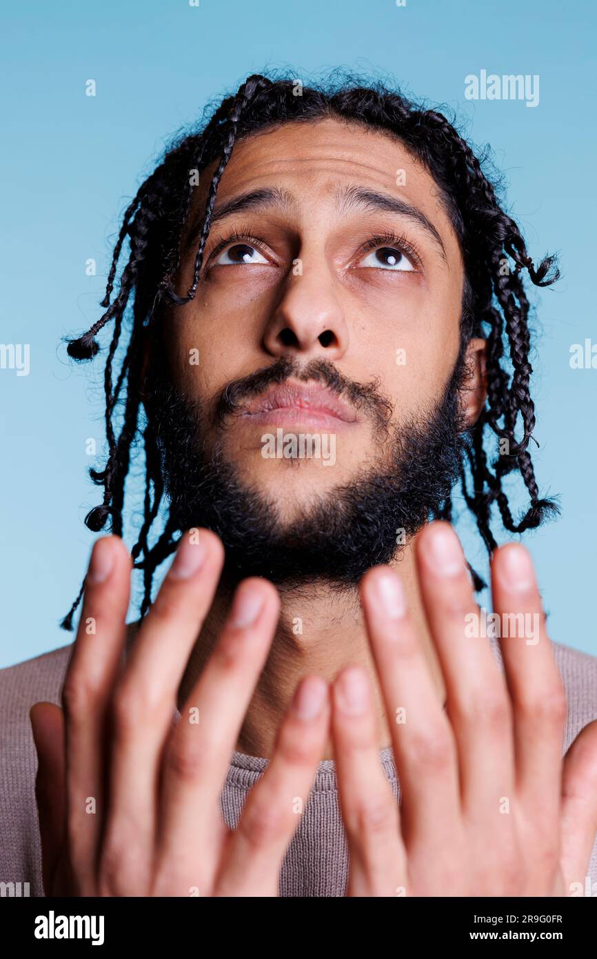 Arab man praying face with hopeful expression and open hands while ...