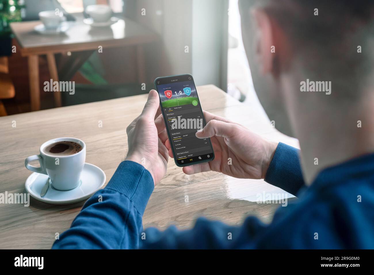 Man follows the online score of the match on his mobile phone in a cafe ...
