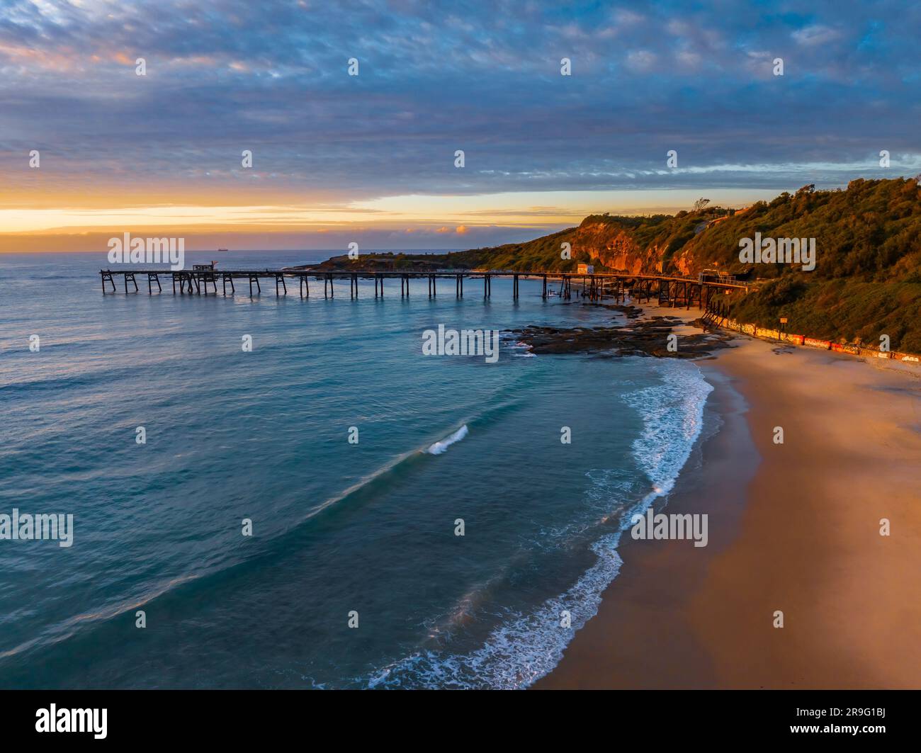 Sunrise seascape with cloud filled sky and the old coal loading jetty ...