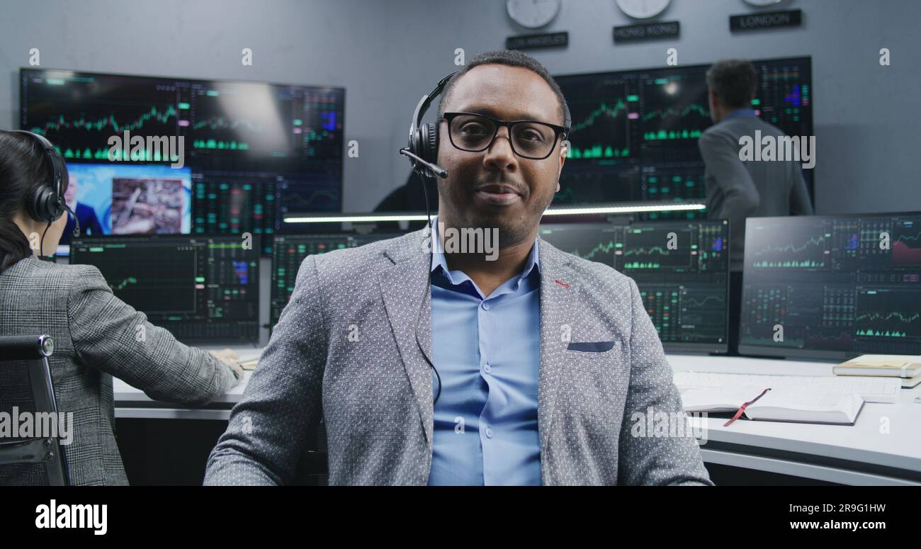 African American financial analyst in headset sits near computer with ...