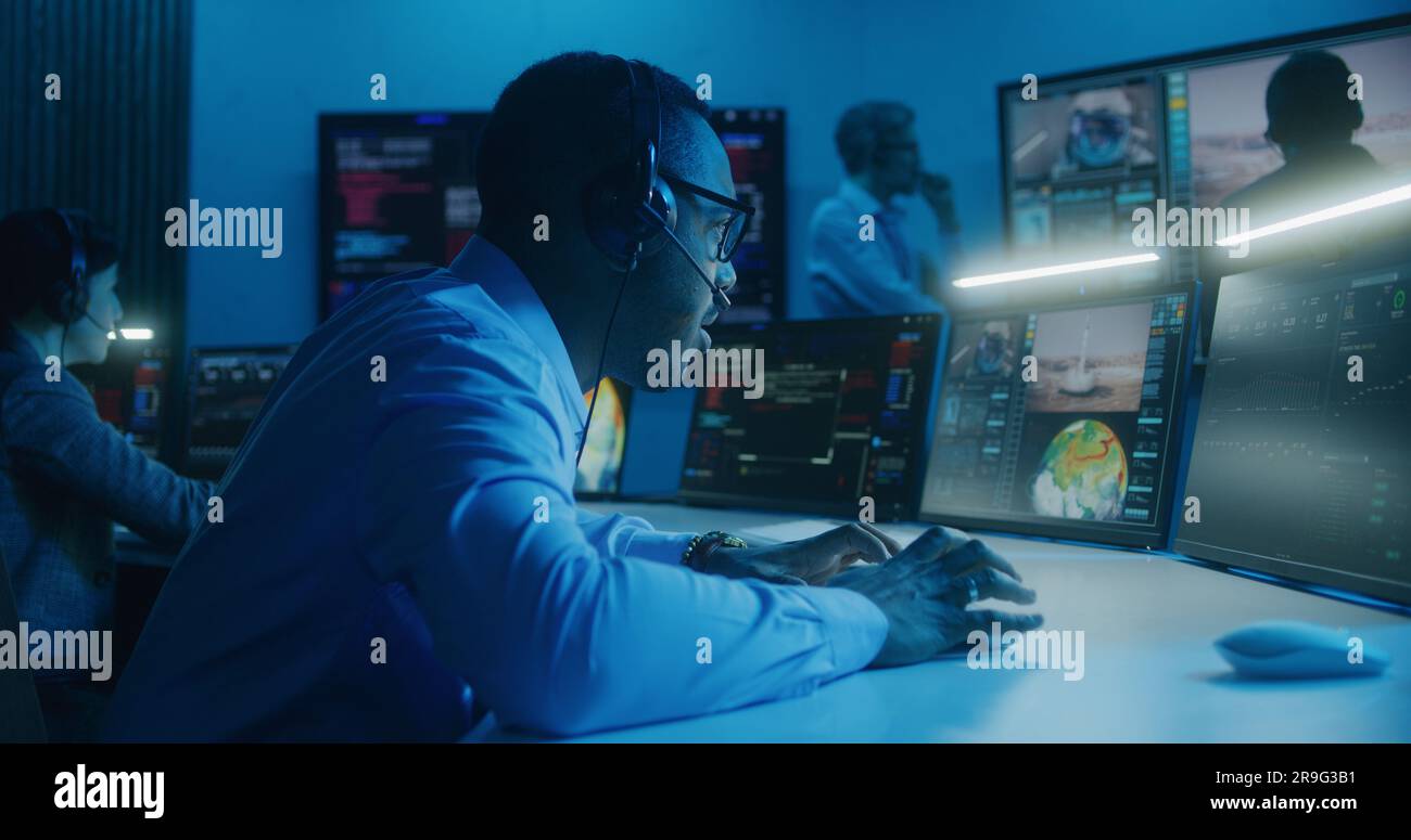 African American flight control employee in headset monitors space ...
