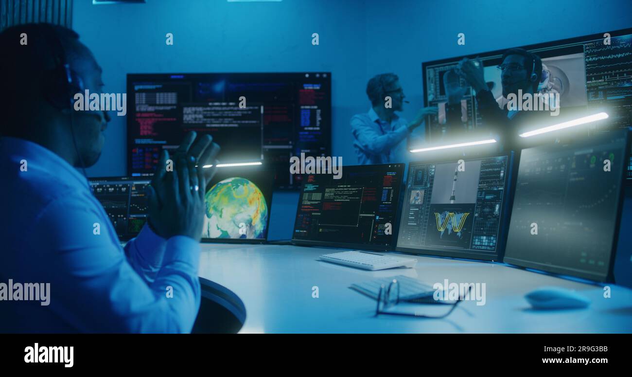 African American flight control employee in headset monitors space ...