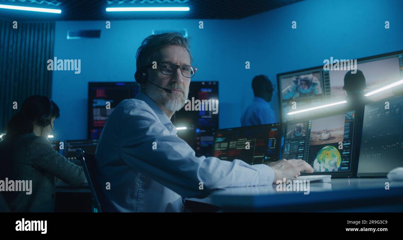 Flight control employee in headset sits in front of computers, monitors ...