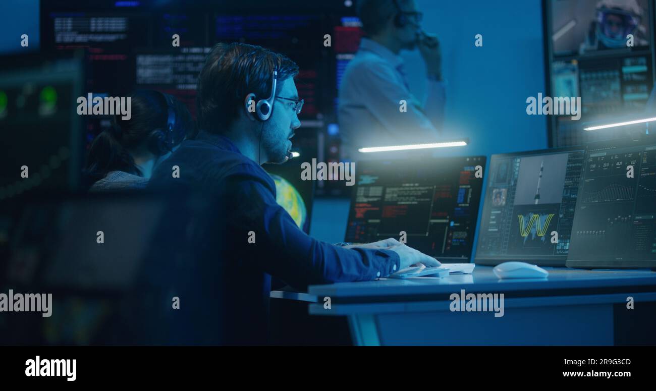 Diverse flight control operators in headsets monitor space mission on ...