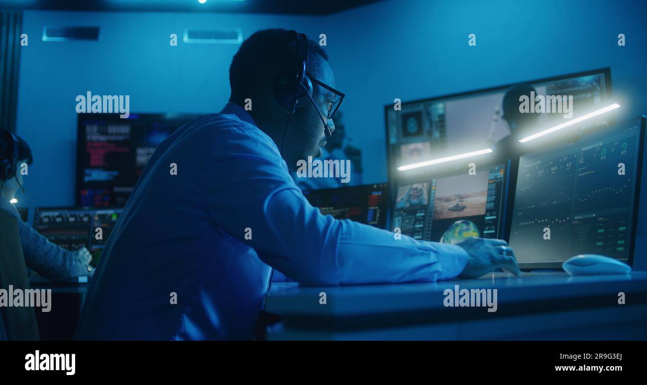 African American flight control employee in headset monitors space ...