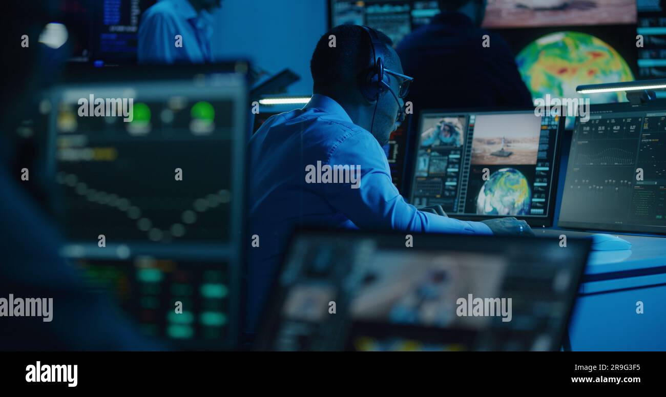 African American flight control employee monitors space mission on ...