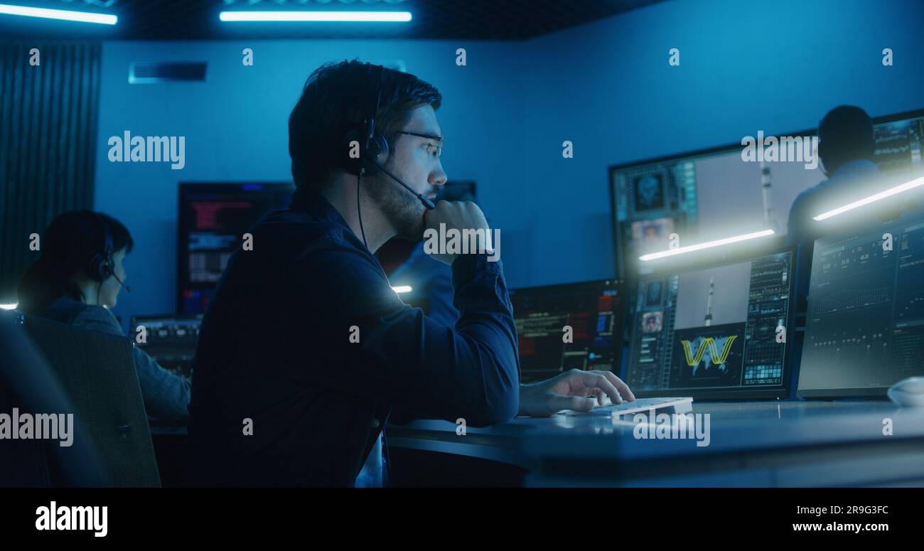 Flight control operator in headset sits in front of computers in ...
