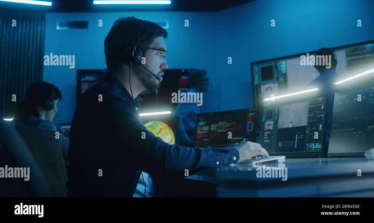 Flight control operator in headset sits in front of computers in ...